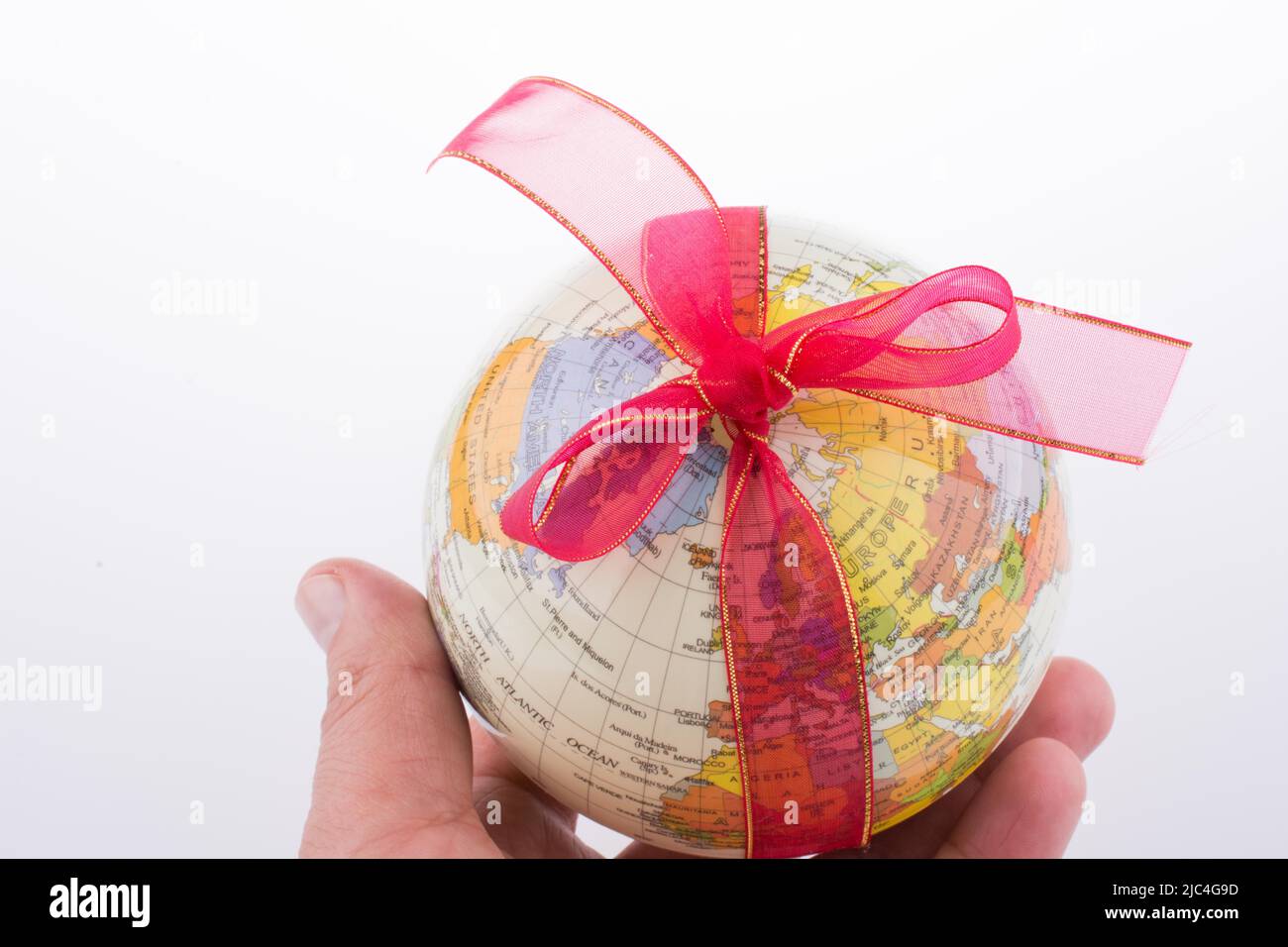 Globe tied with red ribbon on a white background Stock Photo - Alamy