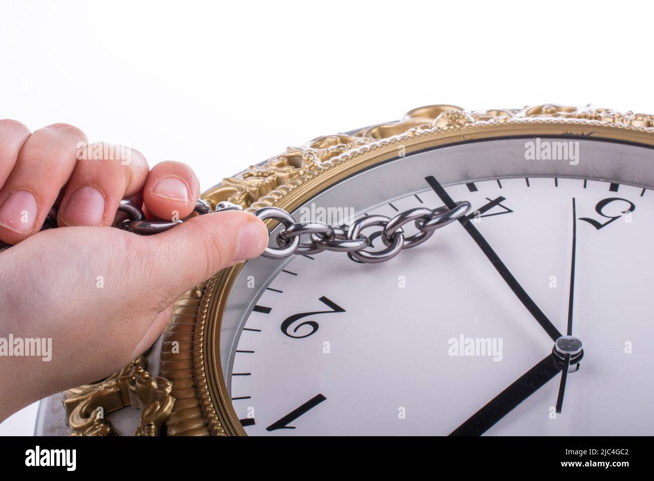 Chain tied to minute hand of a clock and pulled on a white background ...