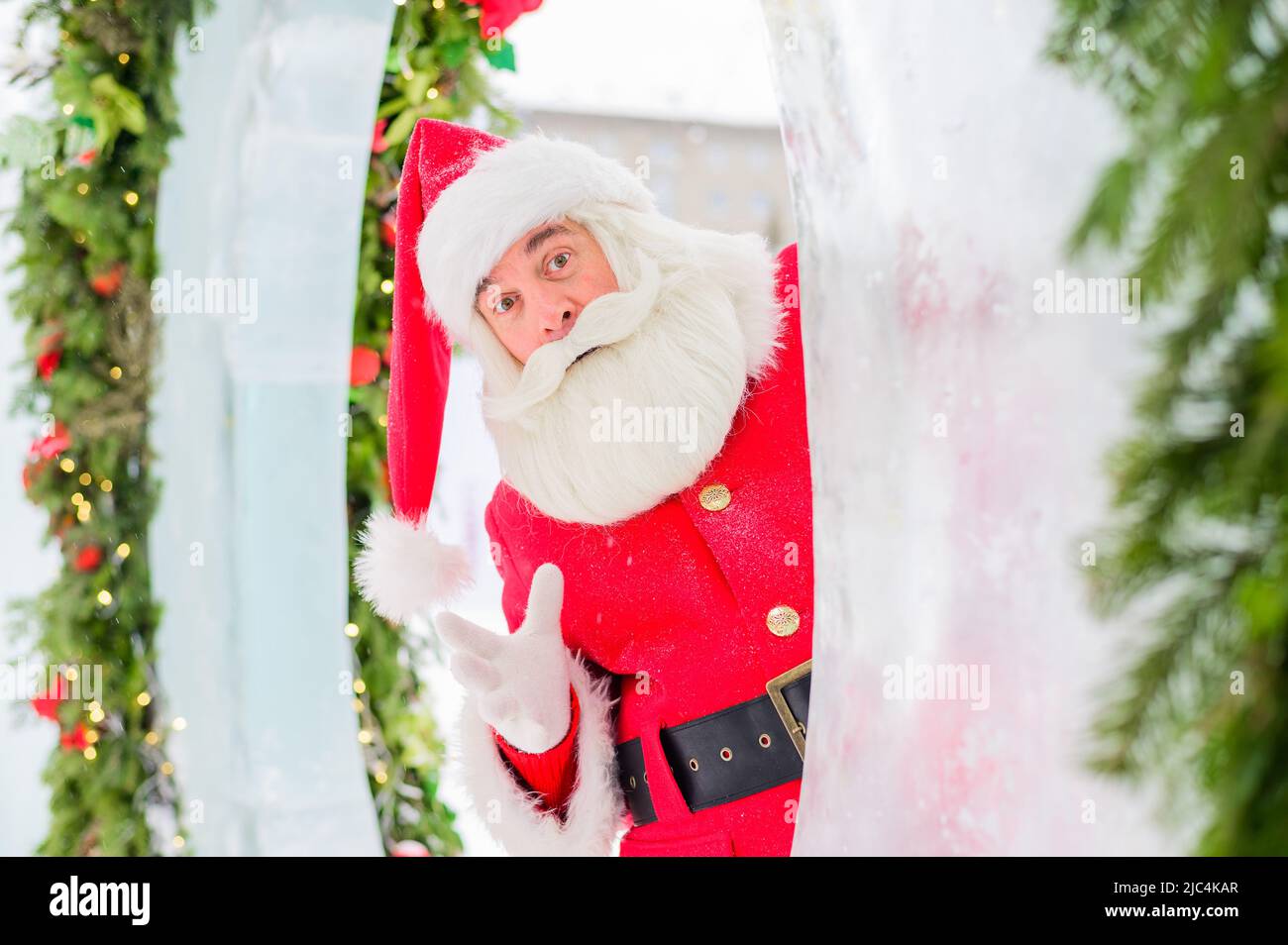 Santa claus peeks out of Christmas decorations outdoors Stock Photo - Alamy