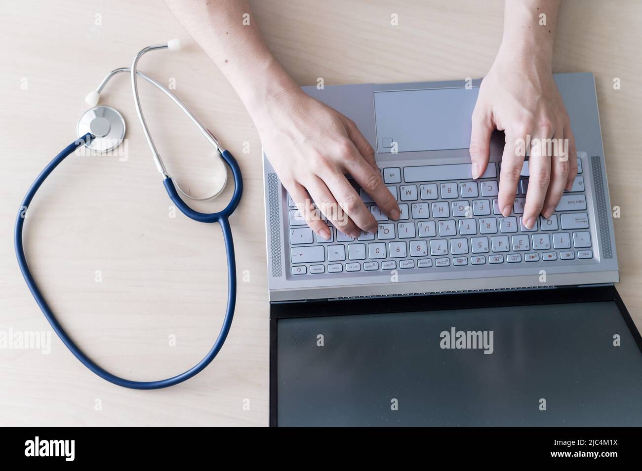 Top view of hands on the keyboard. Woman doctor at the desk typing on a ...