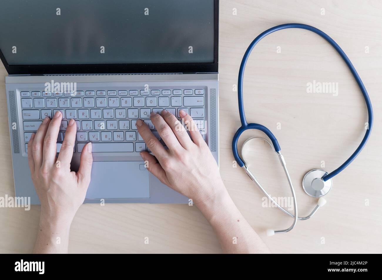 Top view of hands on the keyboard. Woman doctor at the desk typing on a ...