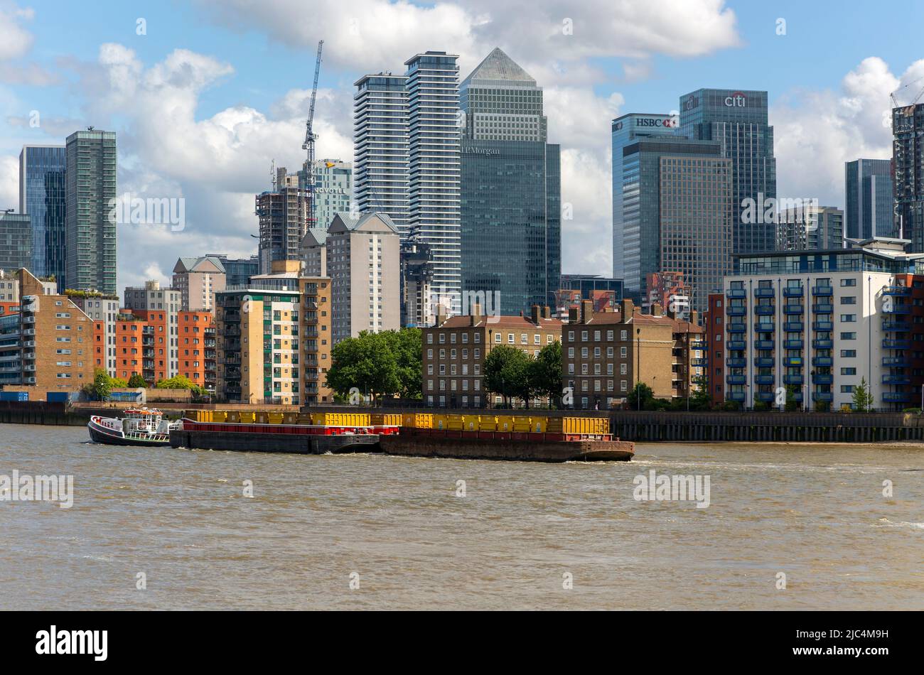 Tug pulling barges carrying shipping containers, River Thames, Canary ...