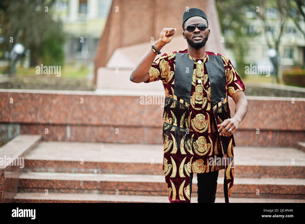 African stylish and handsome man in traditional outfit and black cap ...