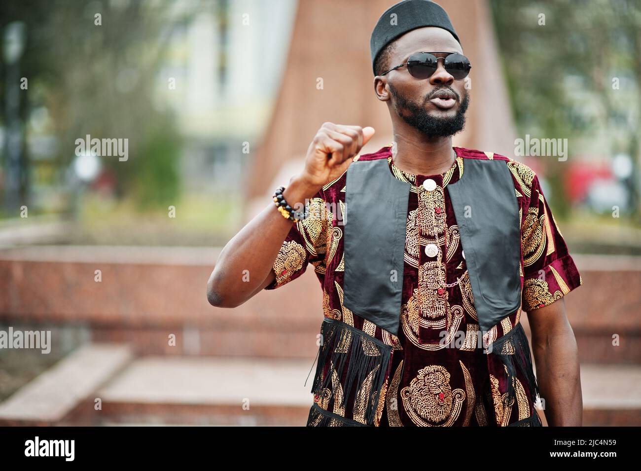African stylish and handsome man in traditional outfit and black cap ...