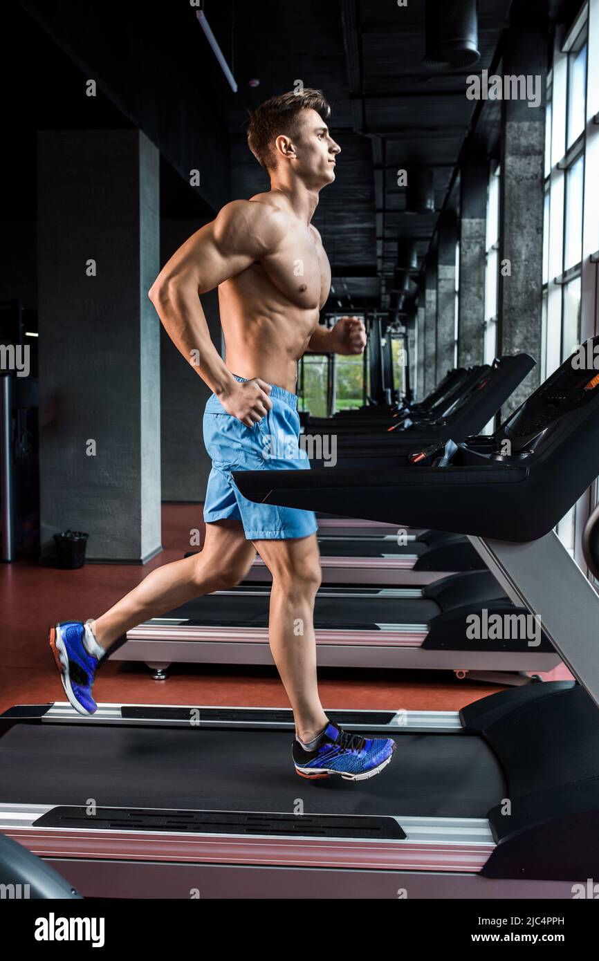 Young adult man running on treadmill in gym Stock Photo - Alamy