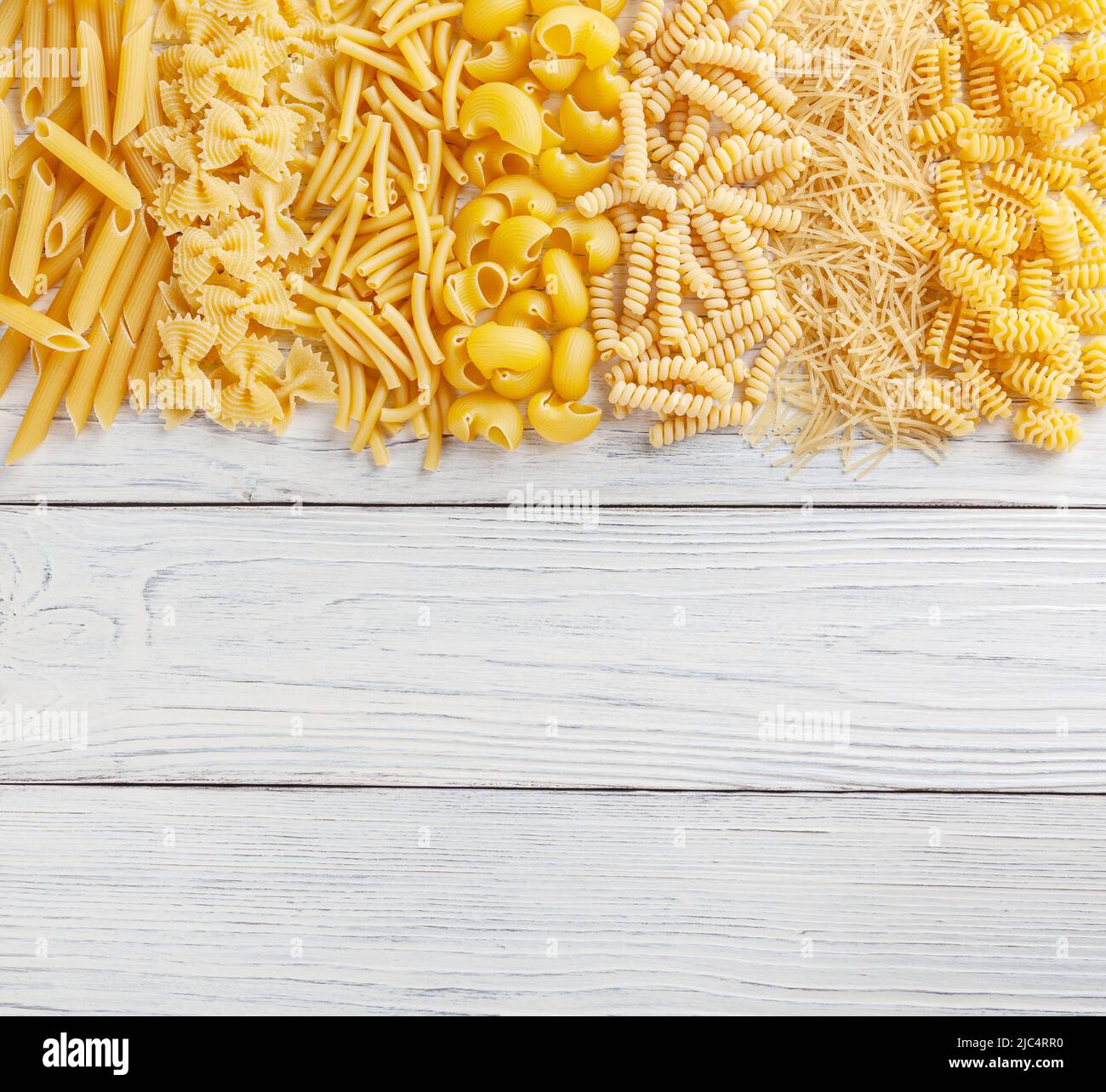 Different types and shapes of Italian pasta on white wooden background ...
