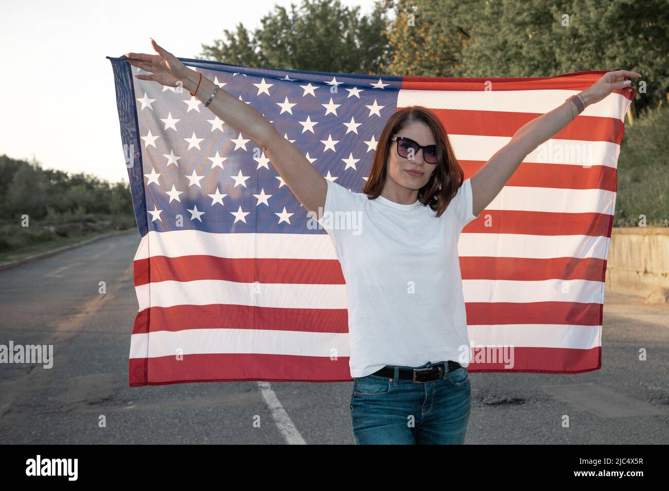 Beautiful young woman under USA flag. Woman standing and holding ...