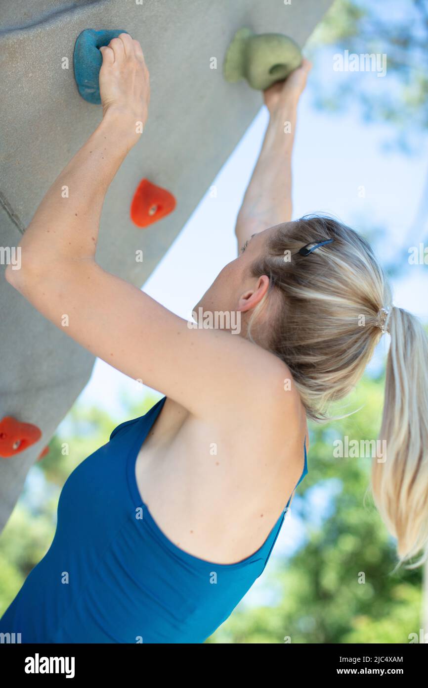 beautiful young woman starts to climbing big artificial wall Stock ...