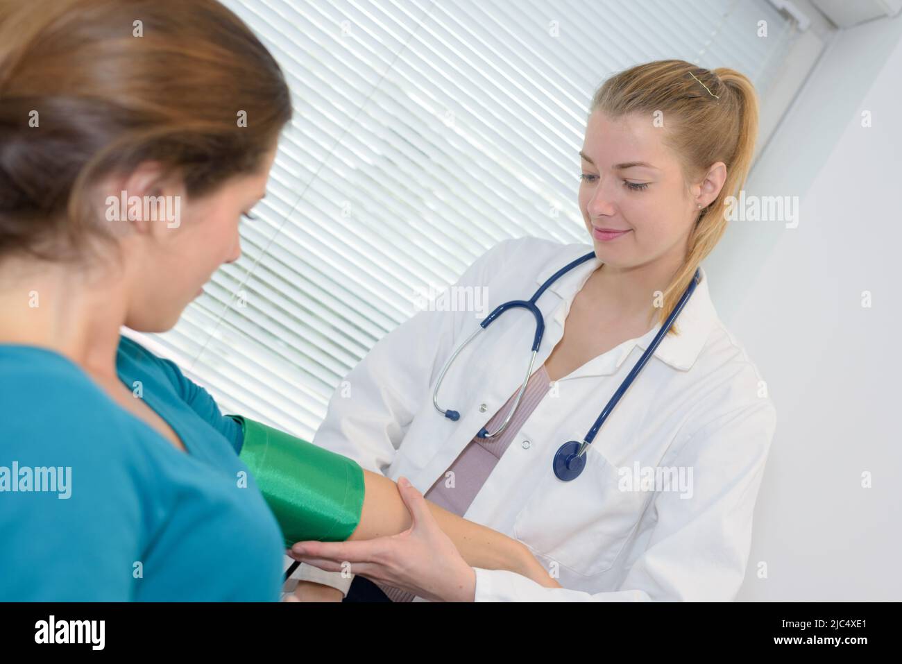 female doctor checking young woman blood pressure Stock Photo - Alamy