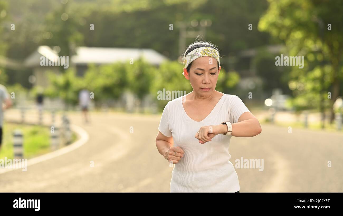 Athletic middle aged woman checking heart rate data on smartwatch ...