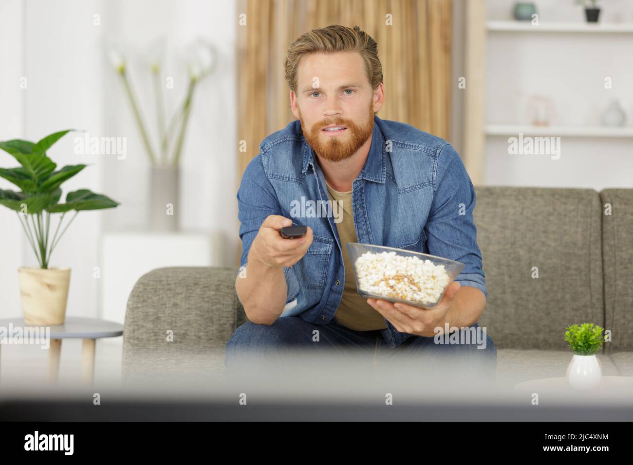 man eating popcorn on the sofa - studio shoot Stock Photo - Alamy
