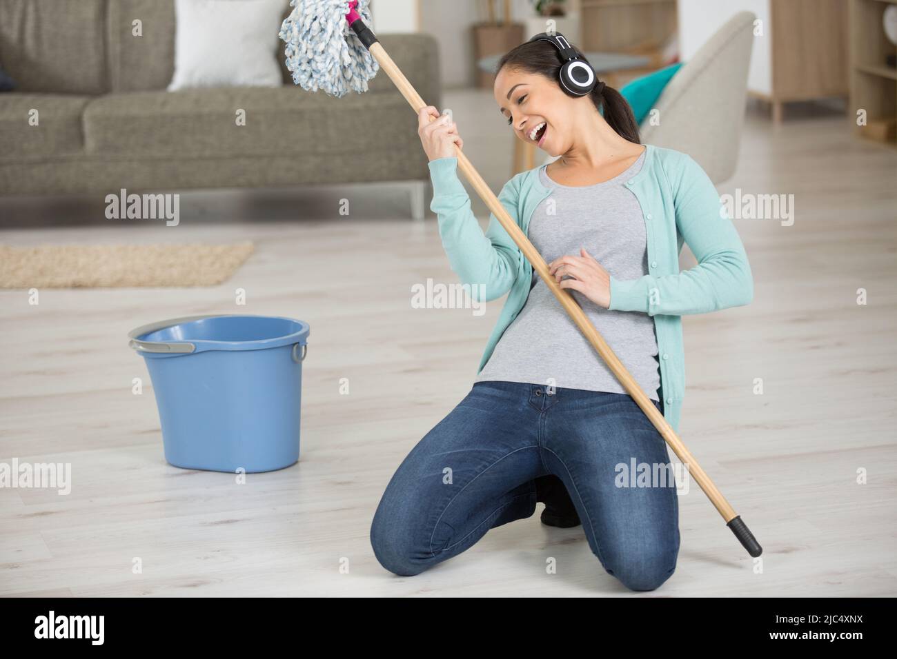 woman having fun playing air guitar on a mop Stock Photo - Alamy
