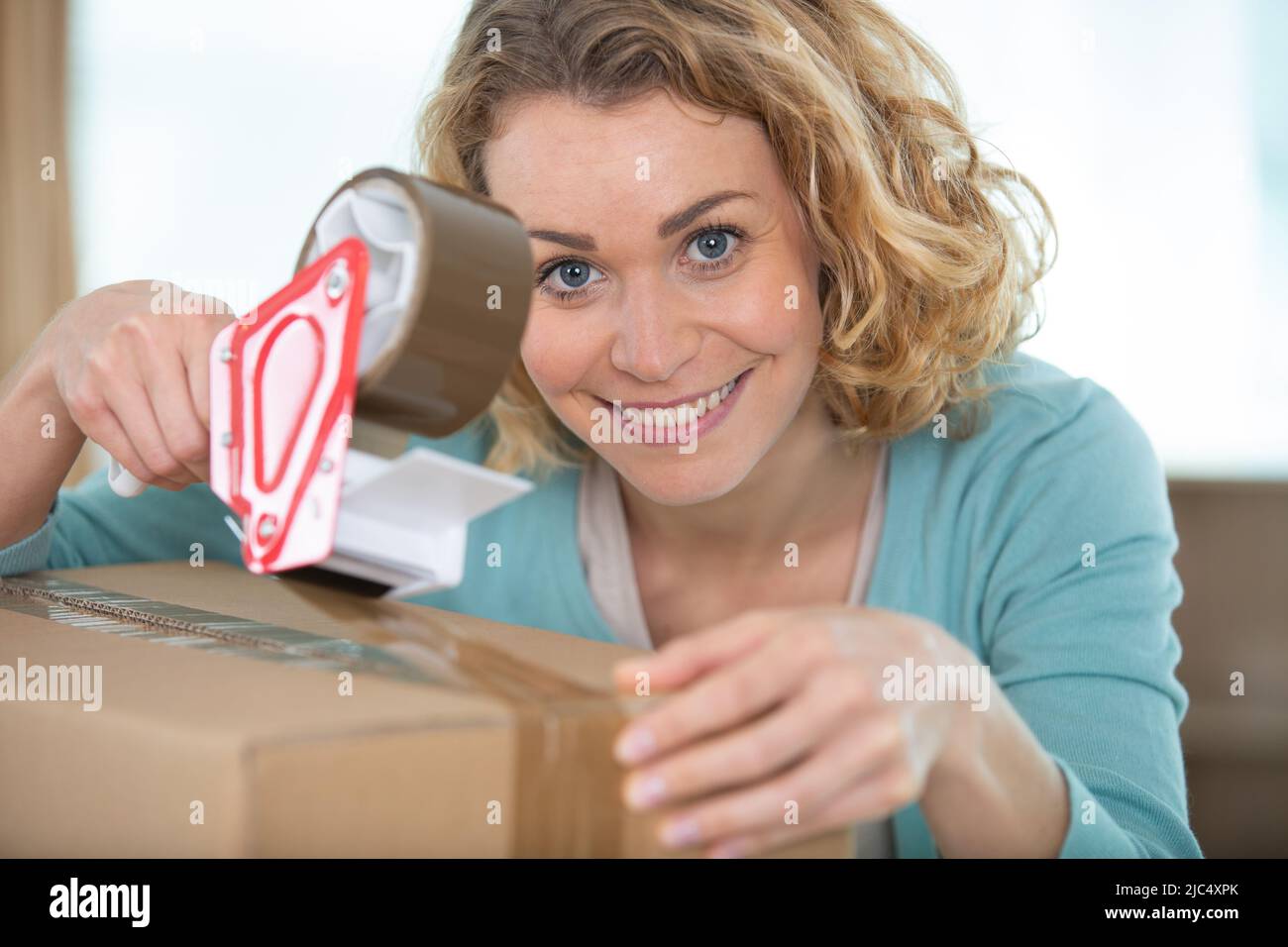 happy young woman closing a cardboard box with tape Stock Photo - Alamy
