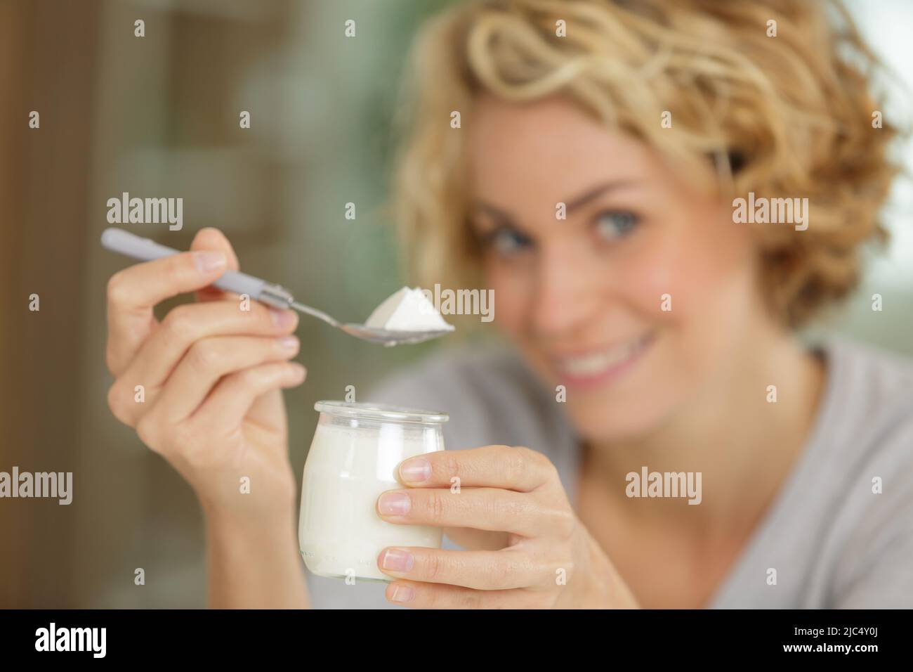 portrait of beautiful young woman eating yogurt at home Stock Photo - Alamy