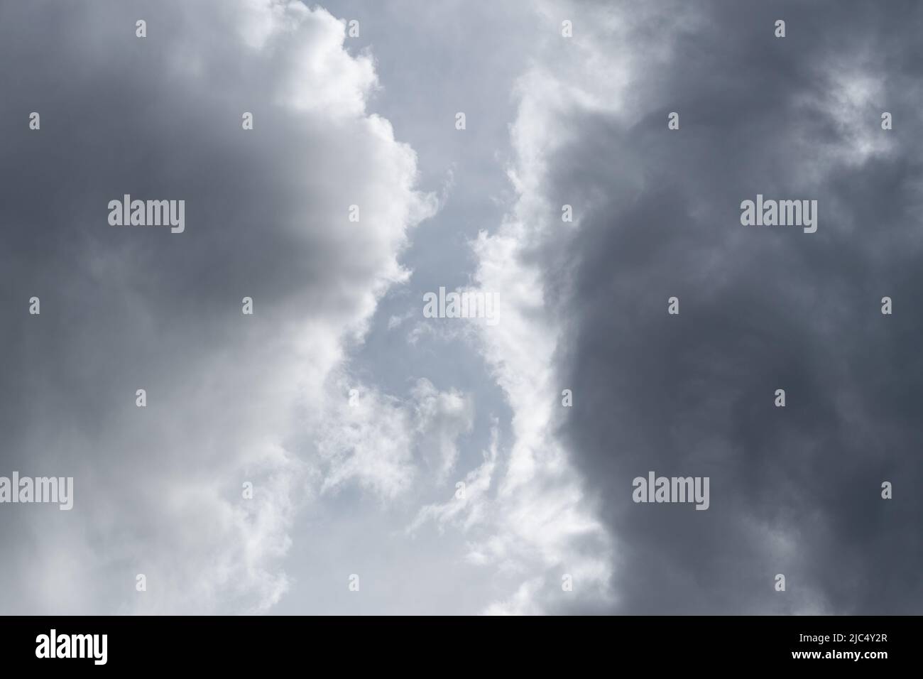 Two grey clouds passing each other with gap in middle, bright edge and ...