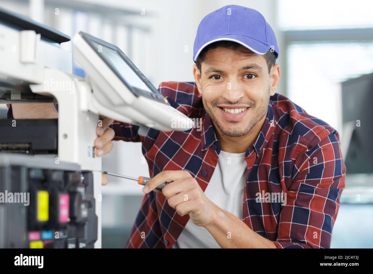 happy worker holds a screwdriver for fixing printer Stock Photo - Alamy
