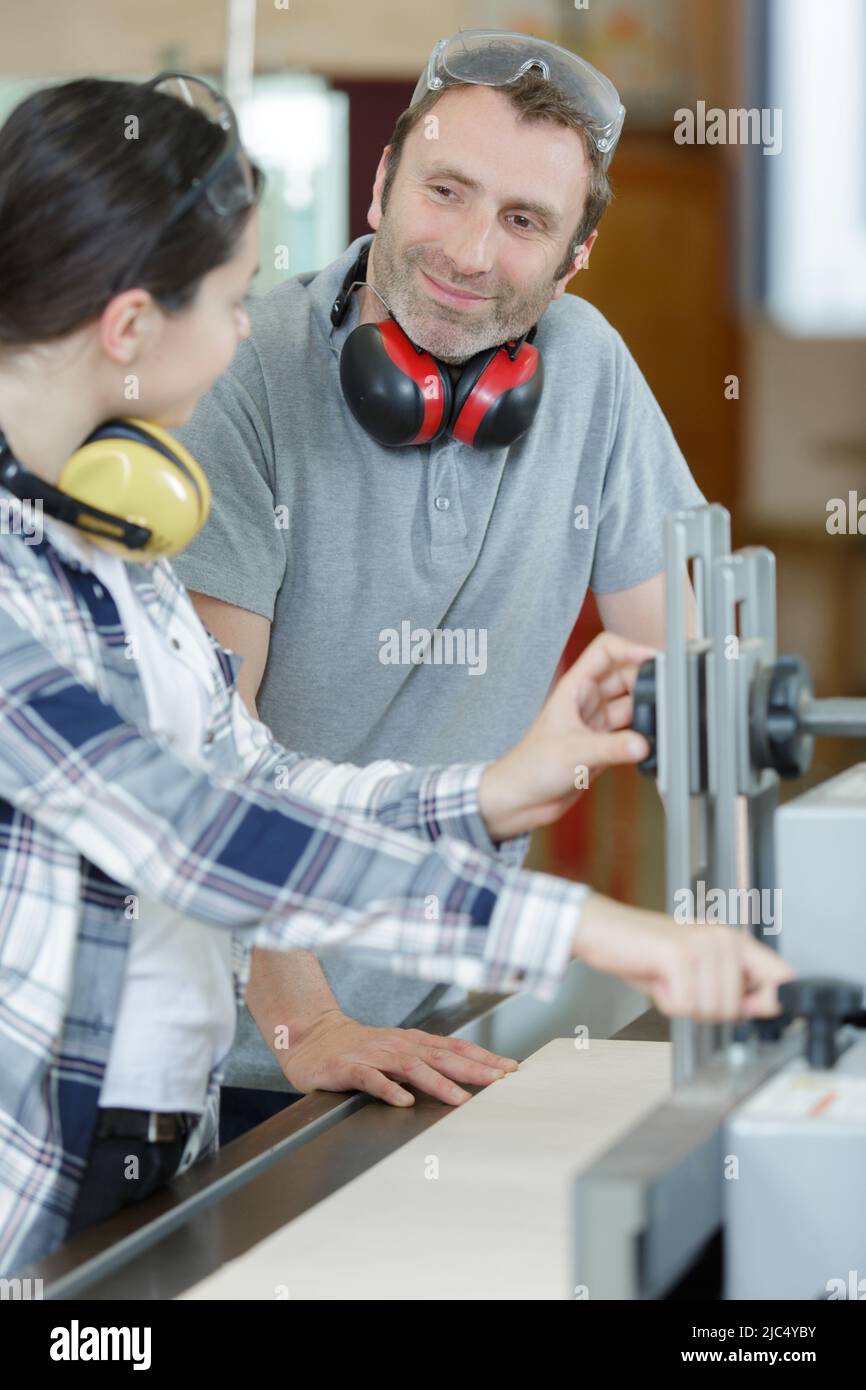 modern artisan teaching female apprentice woodworking in carpentry shop ...