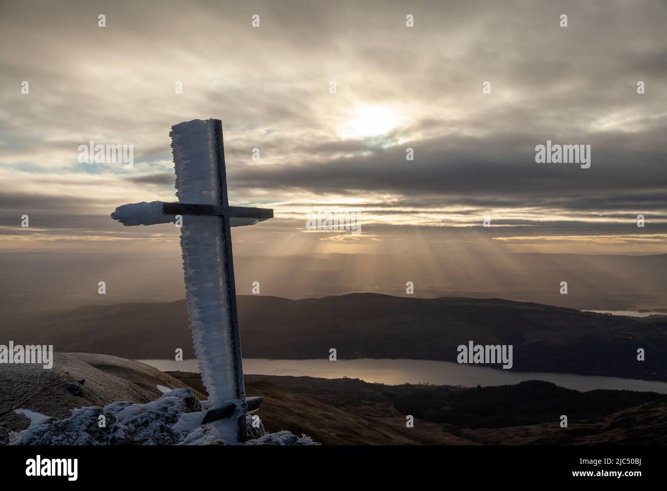 Heaven rays behind a Iron Cross memorial near the summit of Ben Ledi ...