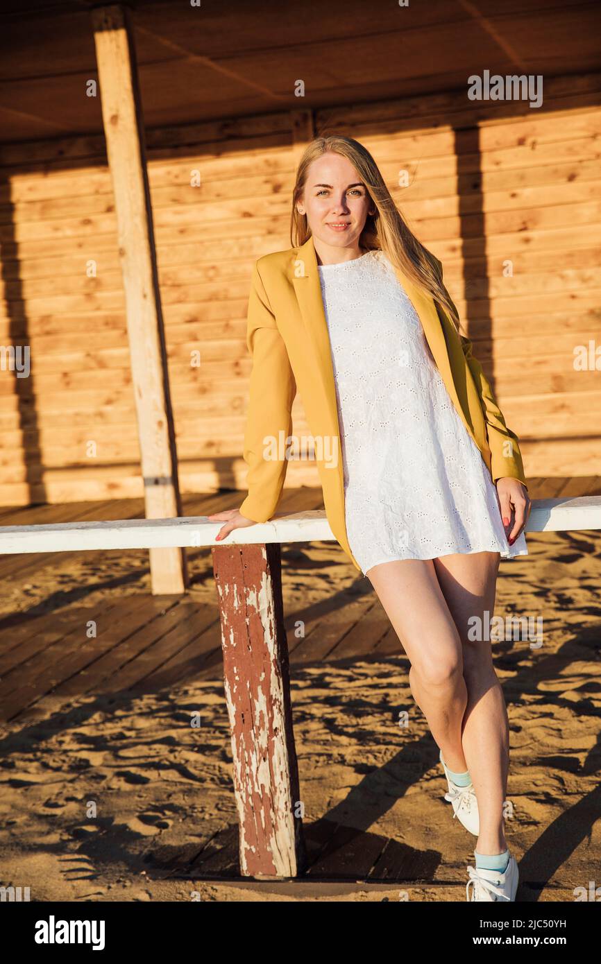 blonde woman in a light summer dress and yellow jacket Stock Photo - Alamy