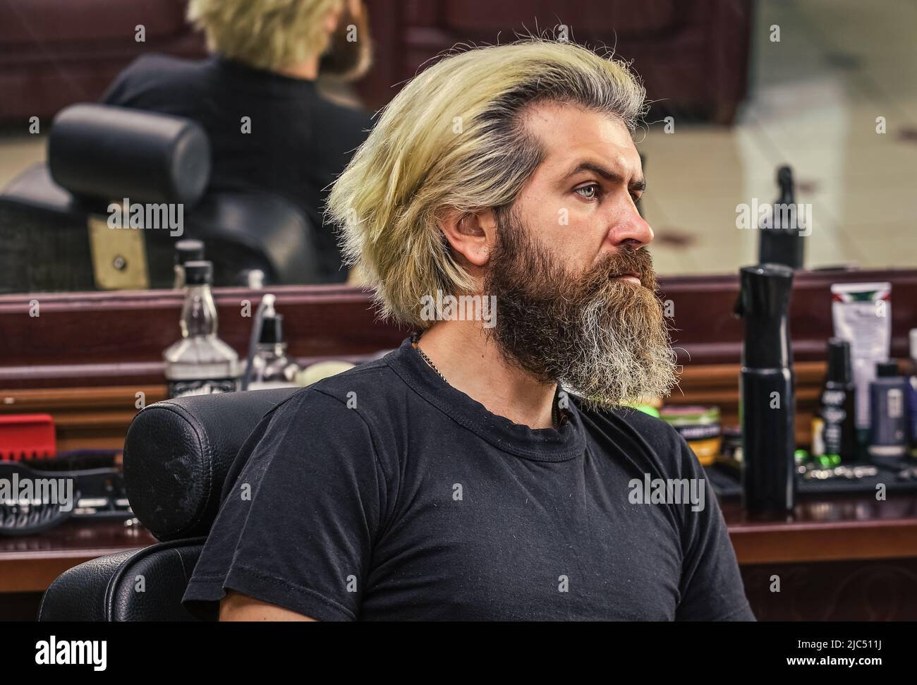 brutal bearded man at hairdresser salon with master, hair look Stock ...