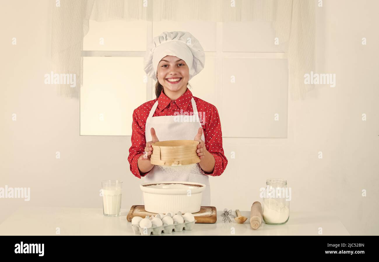 smiling teen girl in chef uniform cooking and baking, cook Stock Photo ...