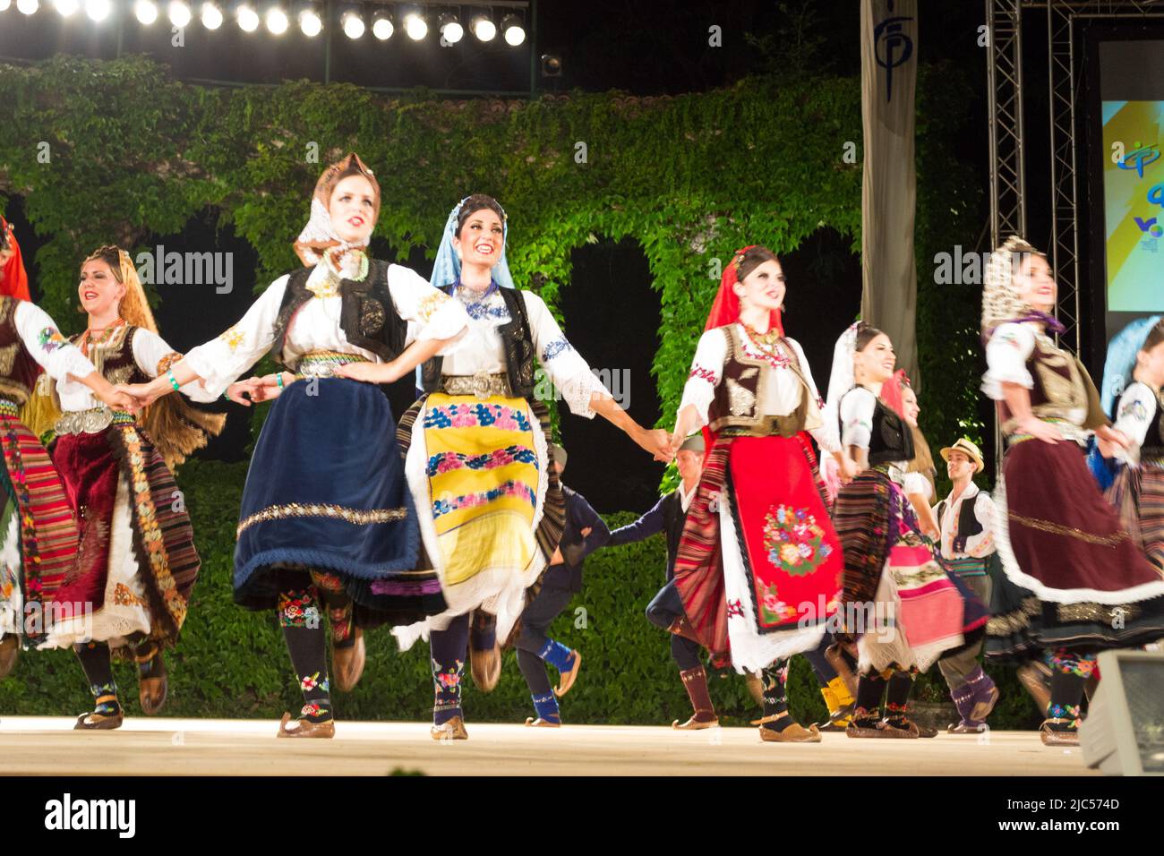 Serbian dancers dressed in traditional costumes performing at the stage ...