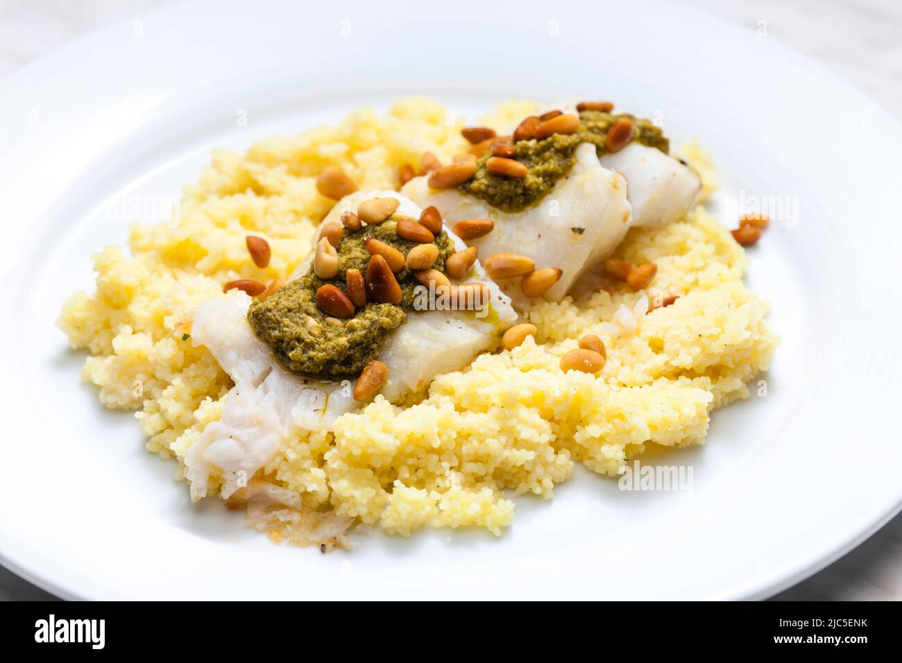 cod with green pesto and pine seeds with couscous Stock Photo - Alamy
