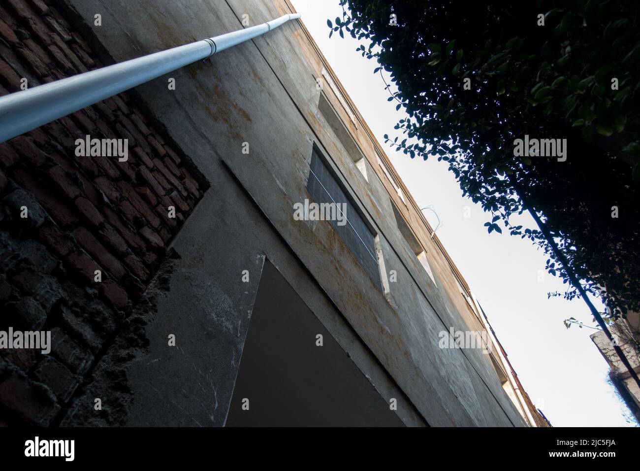 A wide angle shot of a back of a large building with down pipes and big ...