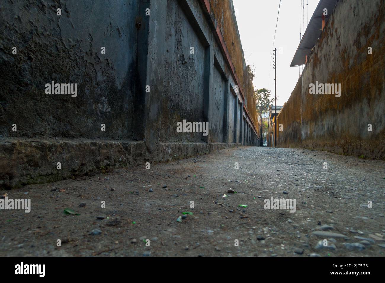 A close-up shot of an empty old narrow lane with big walls on both ...