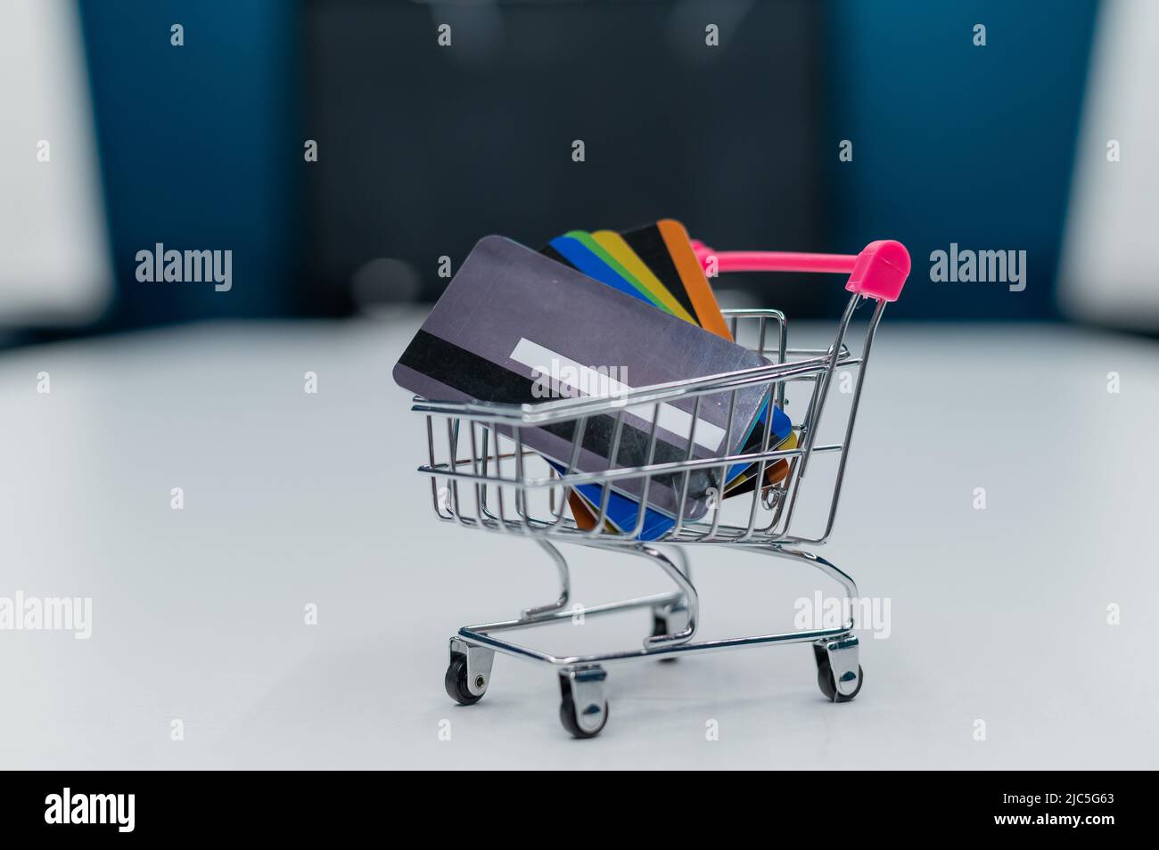 A mini shopping trolley full of credit cards stands on a white table ...