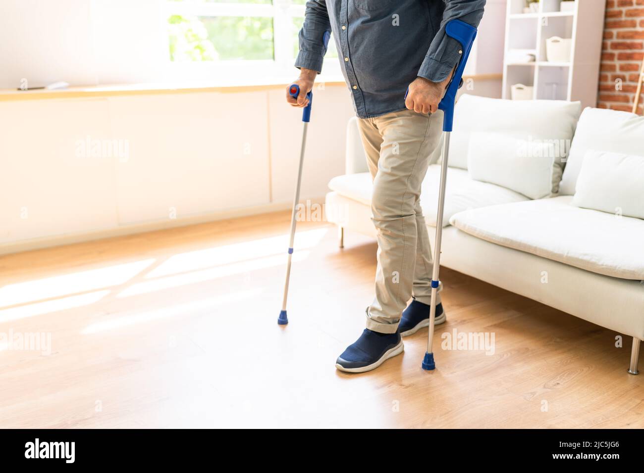 Disabled Man Using Crutches To Walk At Home Stock Photo - Alamy