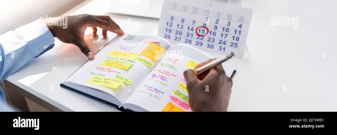Businessman's Hand Checking Schedule In Diary With Calendar On White ...