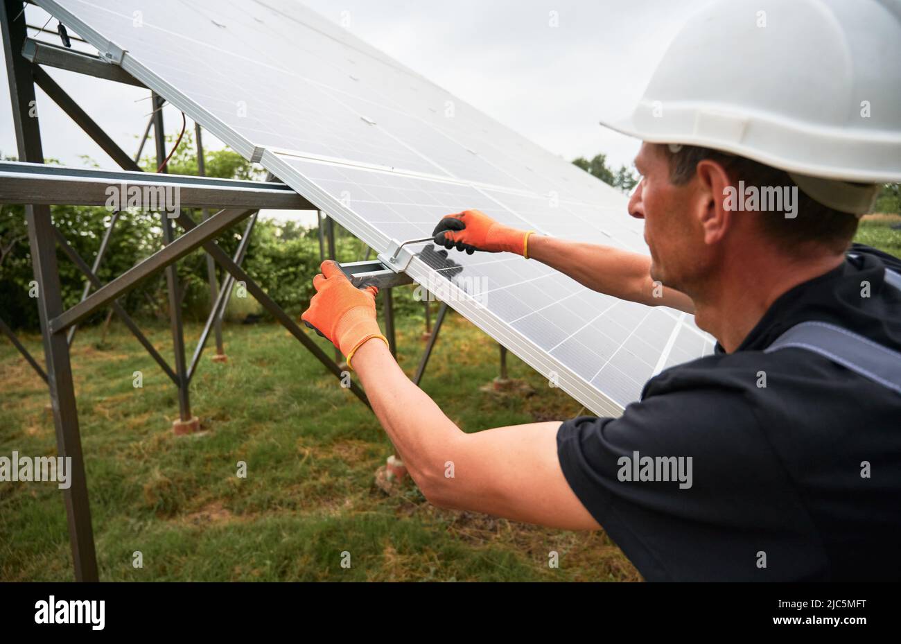 Man engineer installing solar modules. Male worker in safety helmet and ...