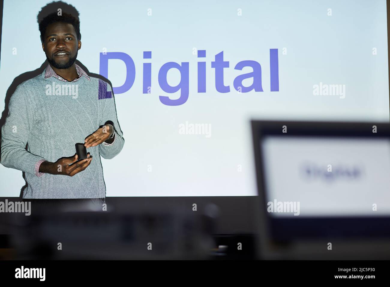 Content confident young Black man in sweater standing by projection ...