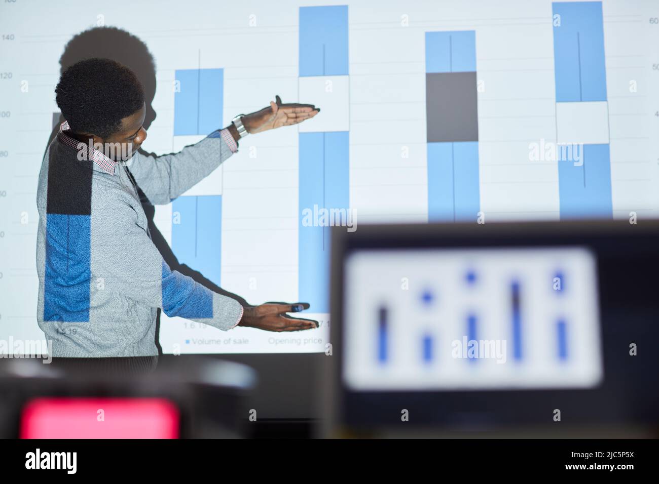Confident experienced Afro-American analyst in sweater gesturing hands ...