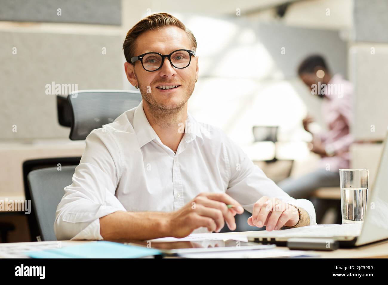 Smiling handsome young male manager with stubble wearing eyeglasses and ...