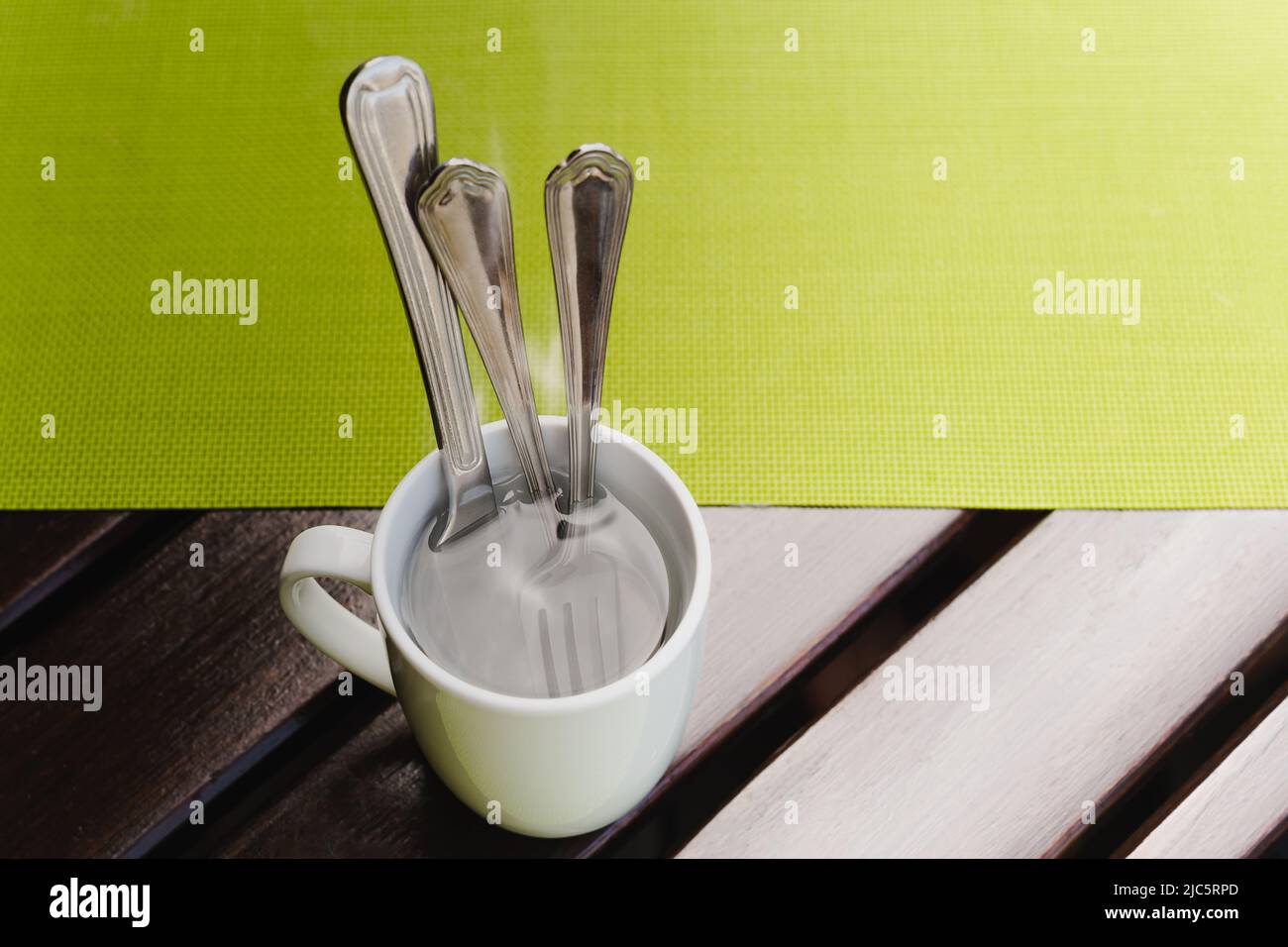 Health and hygiene soaking spoon and fork in hot water in cafe Stock ...