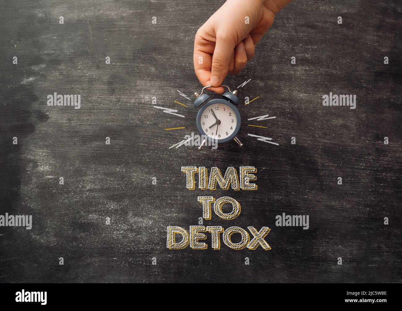 Female hand holds alarm clock above words Time to Detox Stock Photo - Alamy