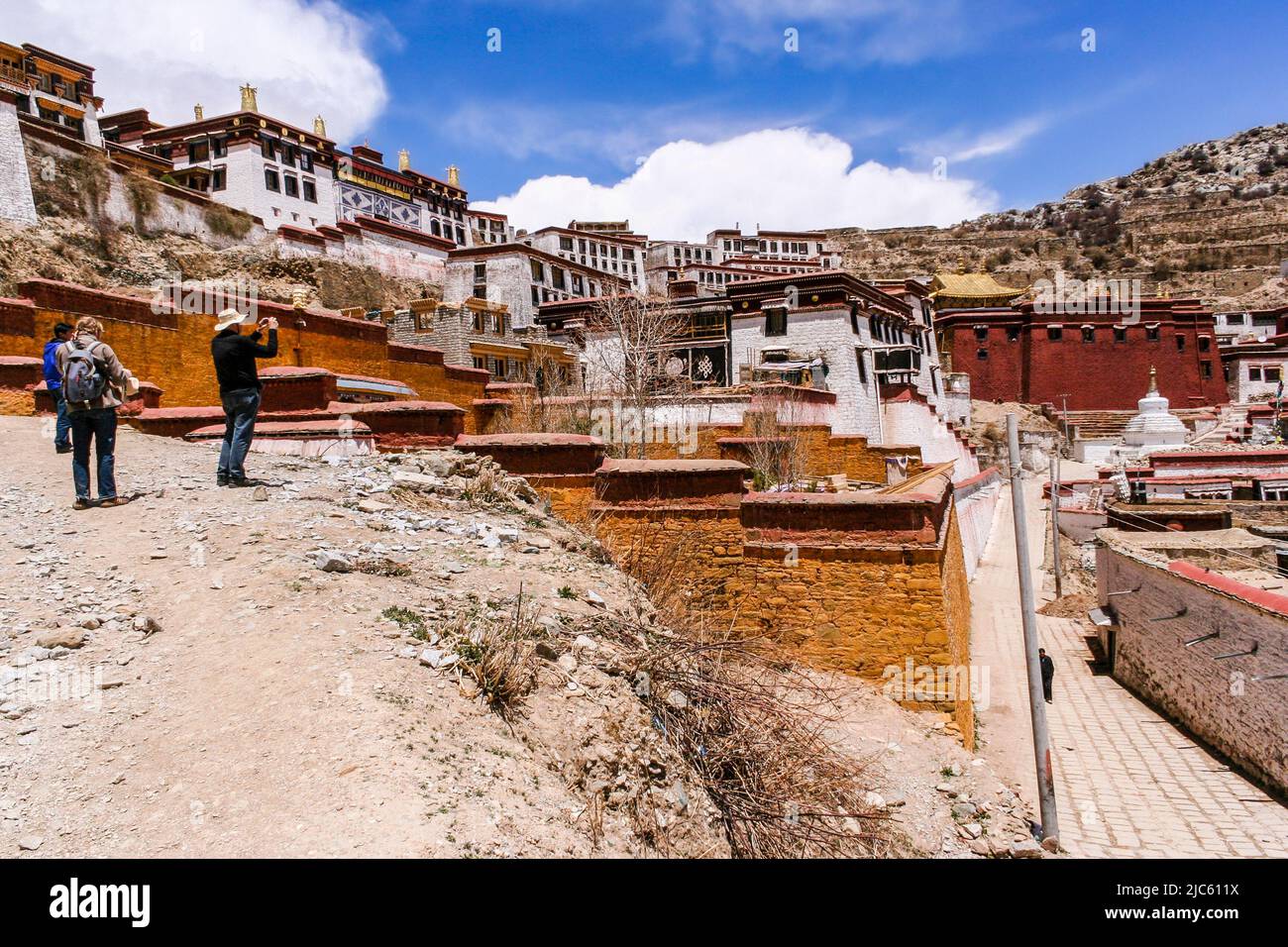 Tourists take photos of Ganden Monastery as they walk around the ...