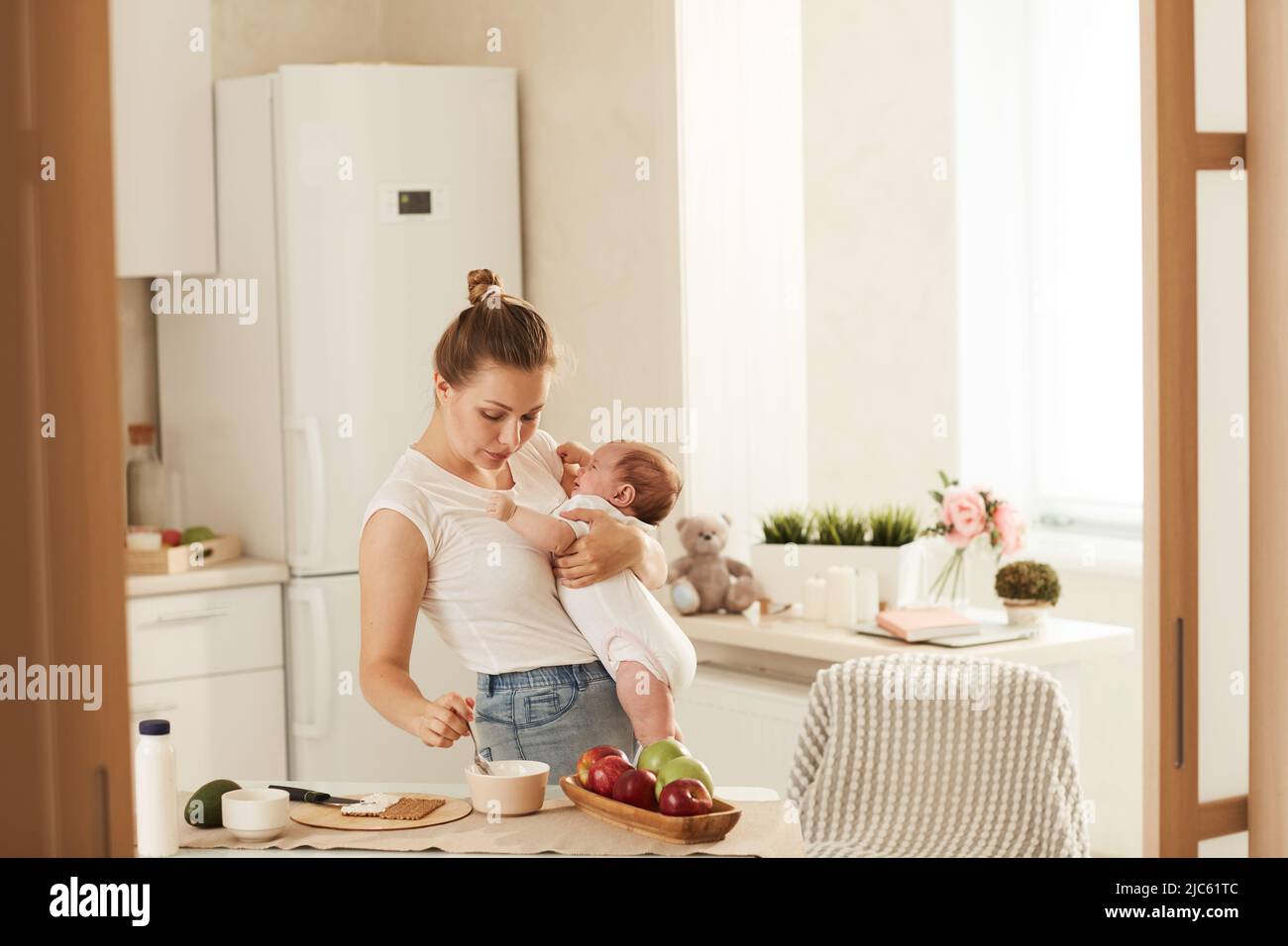 Early breakfast of busy mother in white T-shirt who is trying to eat ...