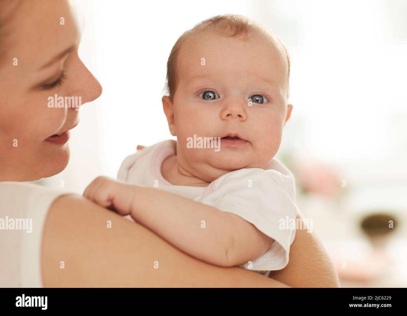 Happy smiling young mother smiling tenderly at her blue-eyed active ...