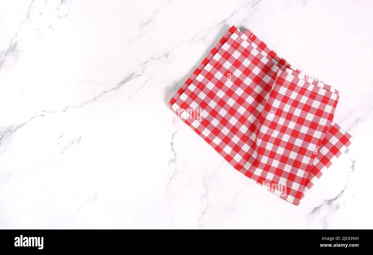 Folded red checkered cloth on white table top view.Picnic towel on ...