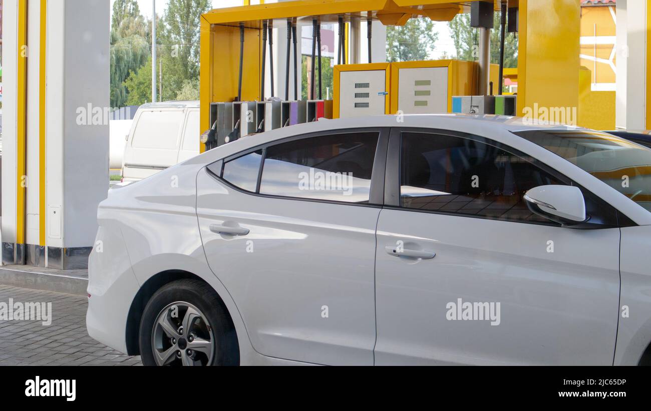 The white car is refueling. Refueling a car parked at a gas station ...