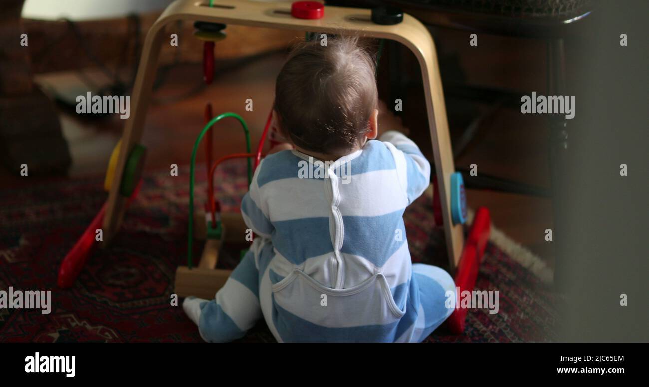 Candid baby playing indoors with toys. Infant sitting down on floor at ...