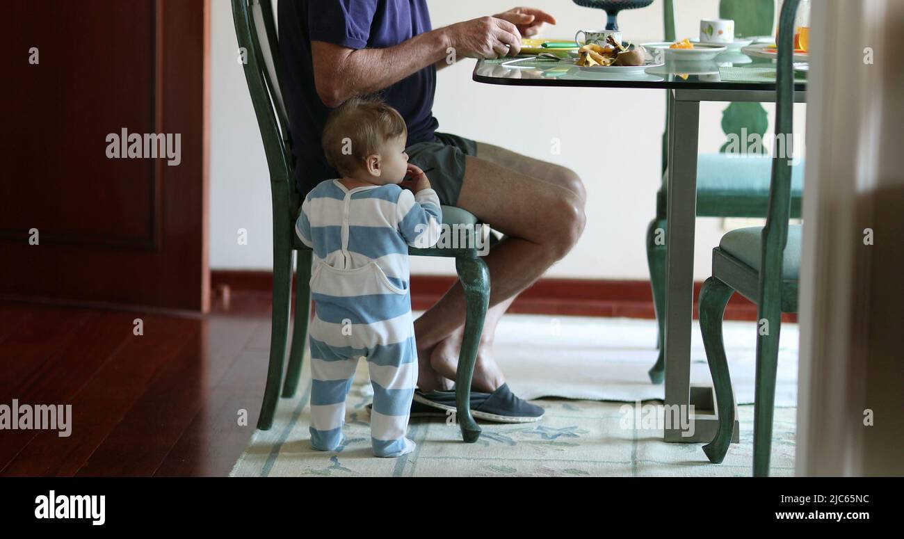 Casual candid grandfather in morning breakfast table with infant boy on ...