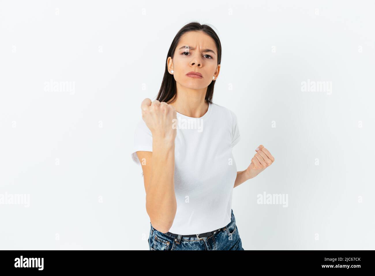 Portrait of serious, angry young woman holding fist in threatening pose ...