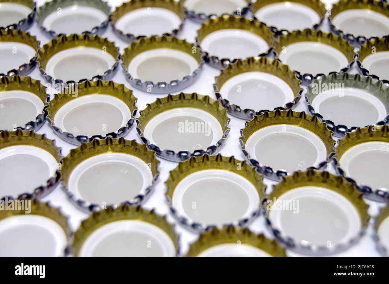 Serrated bottle caps, side by side on white background, selective focus ...