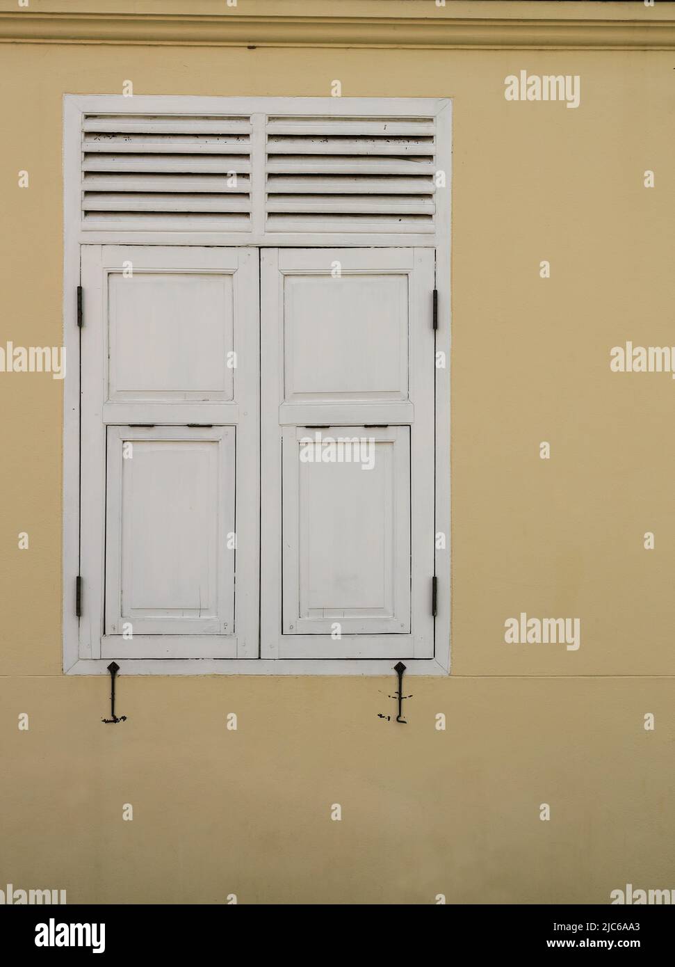 dusty dull yellow ancient building facade with the white wooden windows ...