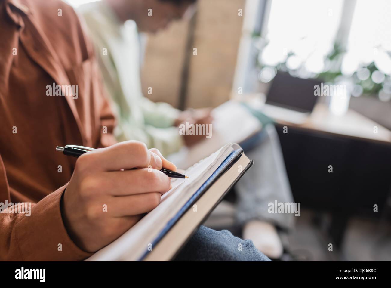 partial view of student writing in notebook on blurred background Stock ...