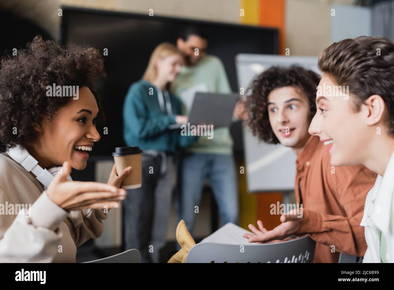 excited african american student with paper cup gesturing during ...